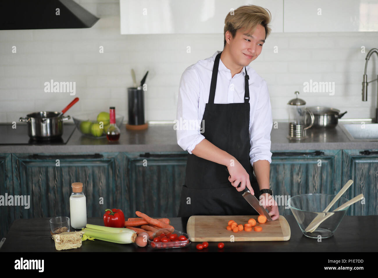 A young Asian cook in the kitchen prepares food in a cook suit Stock ...