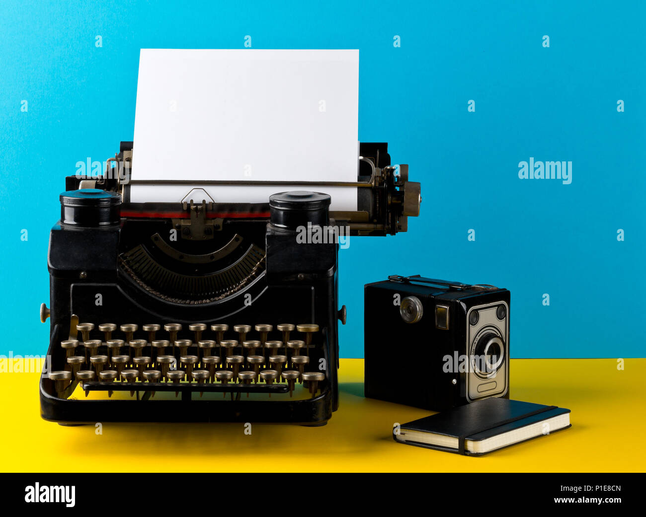 Vintage typewriter with empty, blank sheet of paper, camera and ...