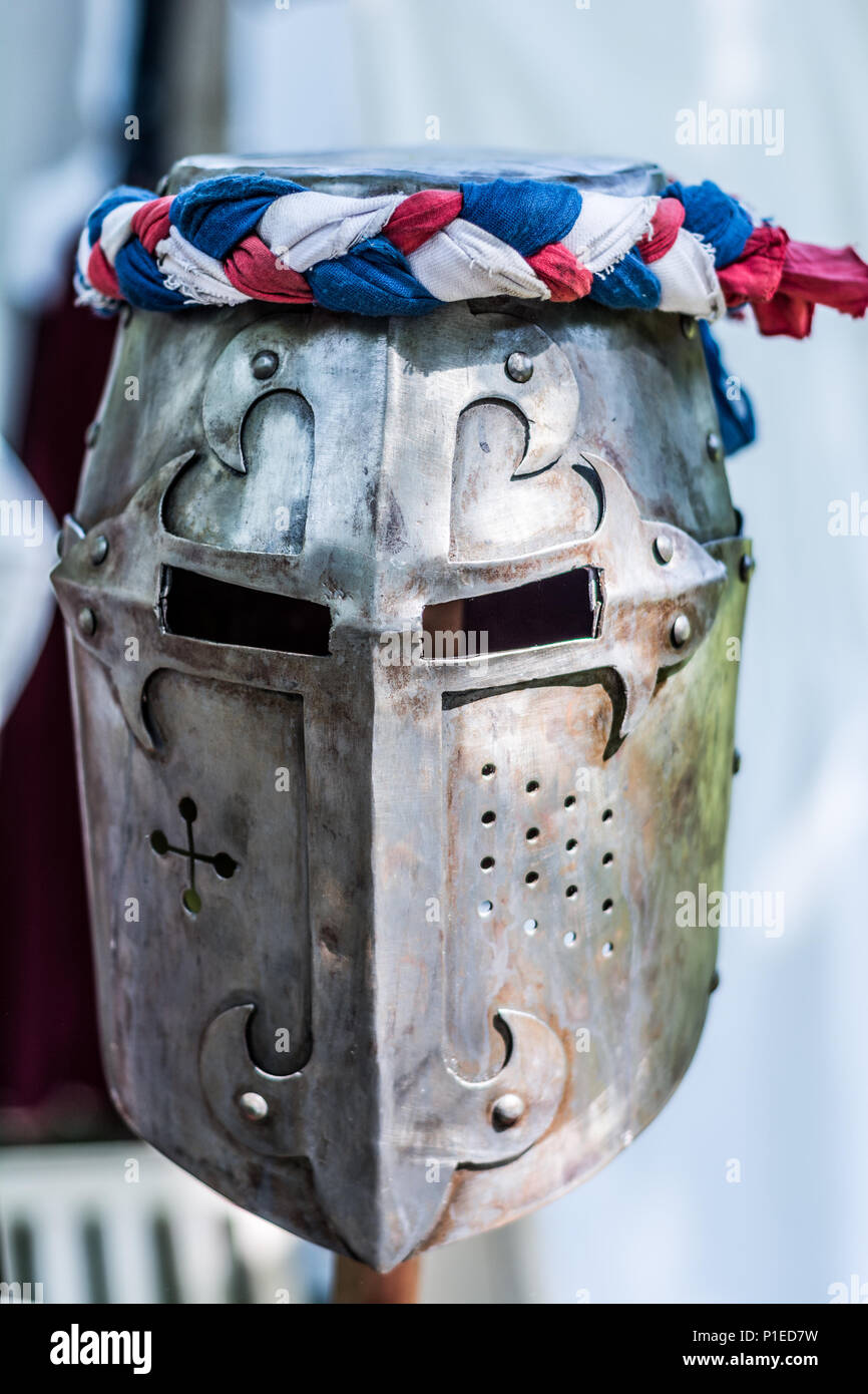 Iron helmet of the medieval knight on wooden stand with red, blue and ...
