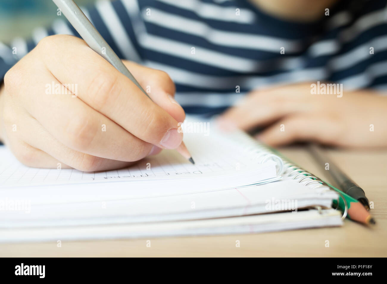 Kid holding pencil and writing in notebook. Close up Stock Photo - Alamy