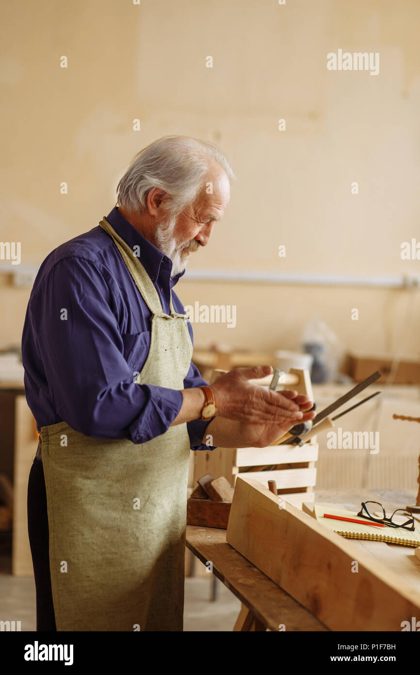 old carpenter is rubbing his hands together after finishing work Stock ...