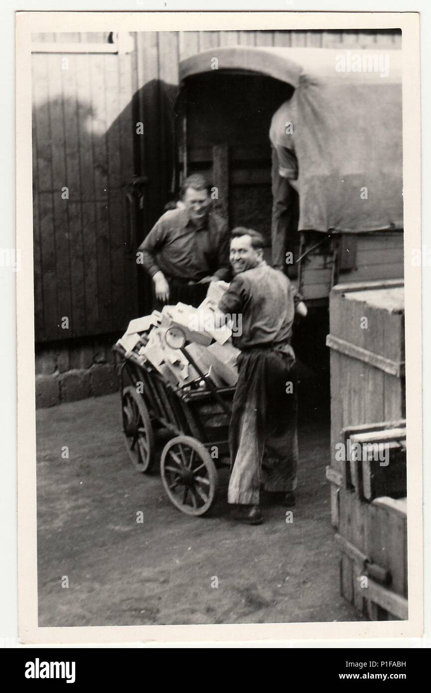 GERMANY - CIRCA 1950s: Vintage photo shows men upload the small boxes ...