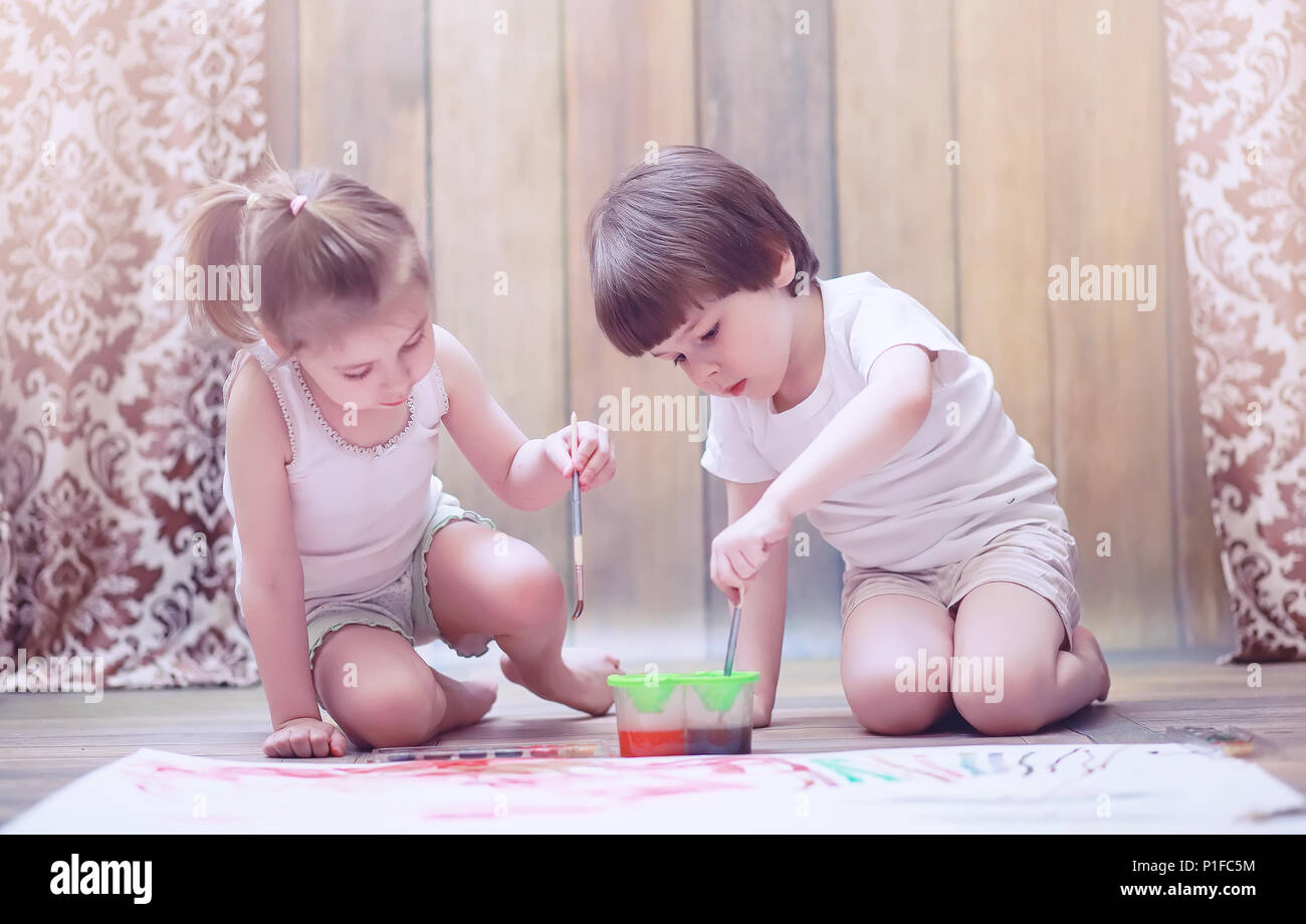 Little children paint on a large sheet of paper on the floor Stock ...