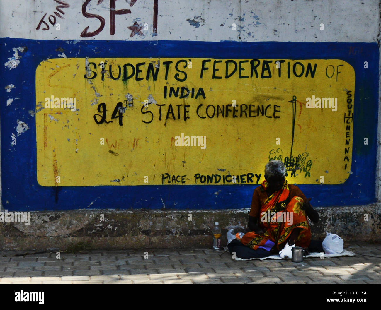 A beggar sitting by a colorful sign in Chennai, India Stock Photo - Alamy