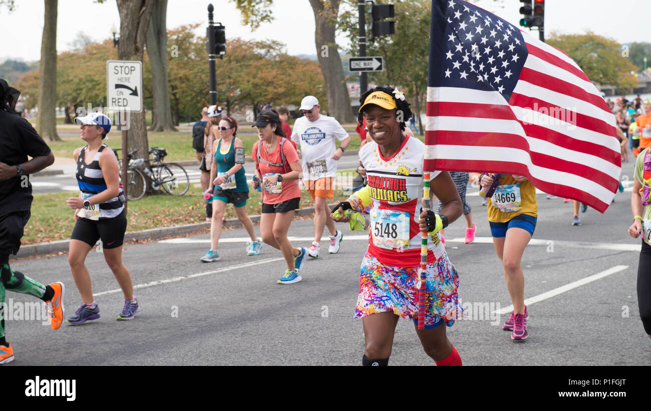 A runner carries the American flag past the 10-mile marker as part of ...