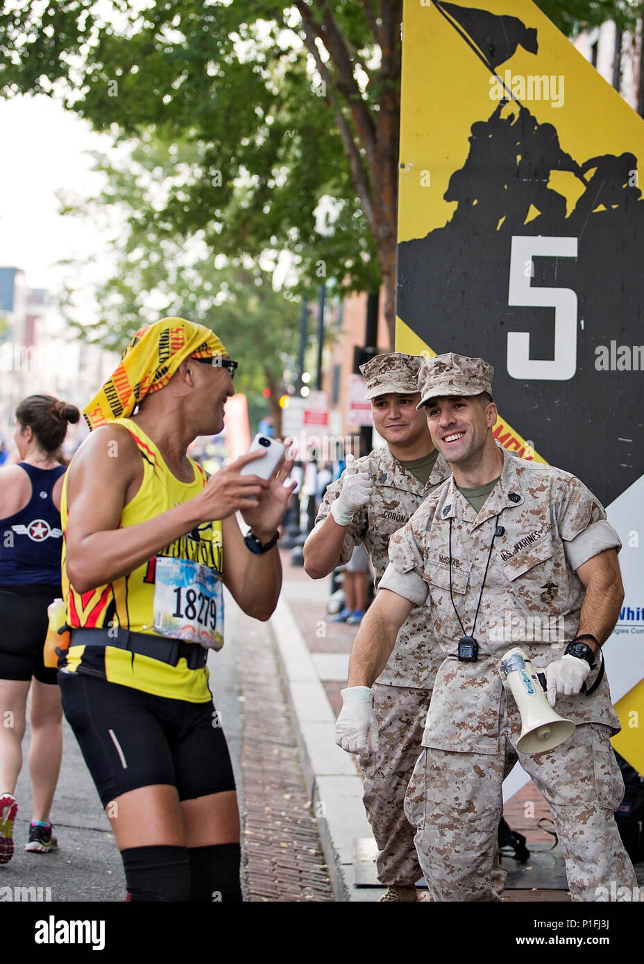A runner poses for a selfie with U.S. Marines at mile marker 5 during ...