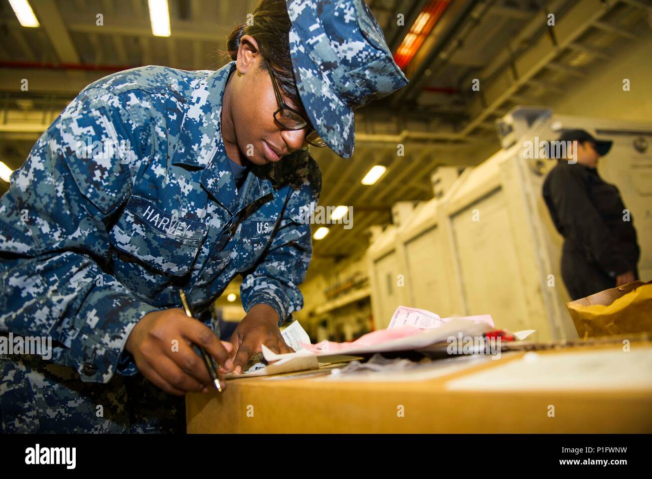 Seaman validates open purchase request forms in the hangar bay of USS ...