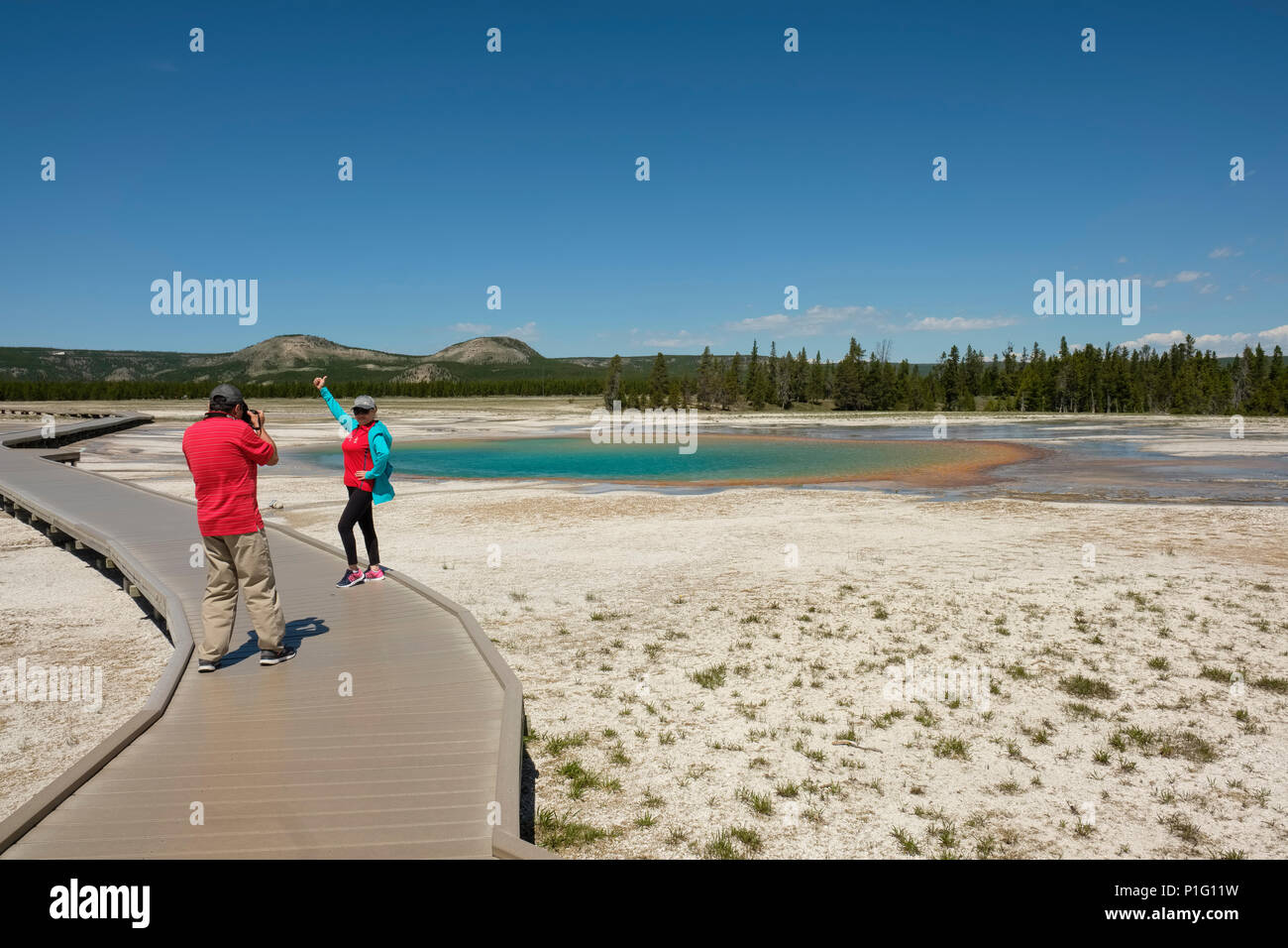 Tourists visiting a hot spring in Yellowstone National Park posing for ...