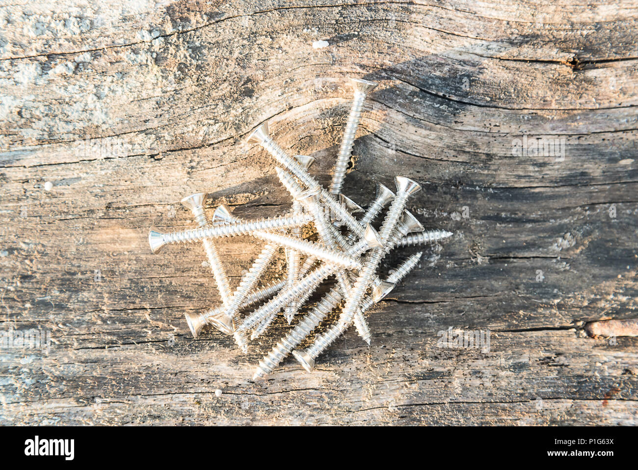 Tapping screws made of steel on wood background at gold sun light Stock ...