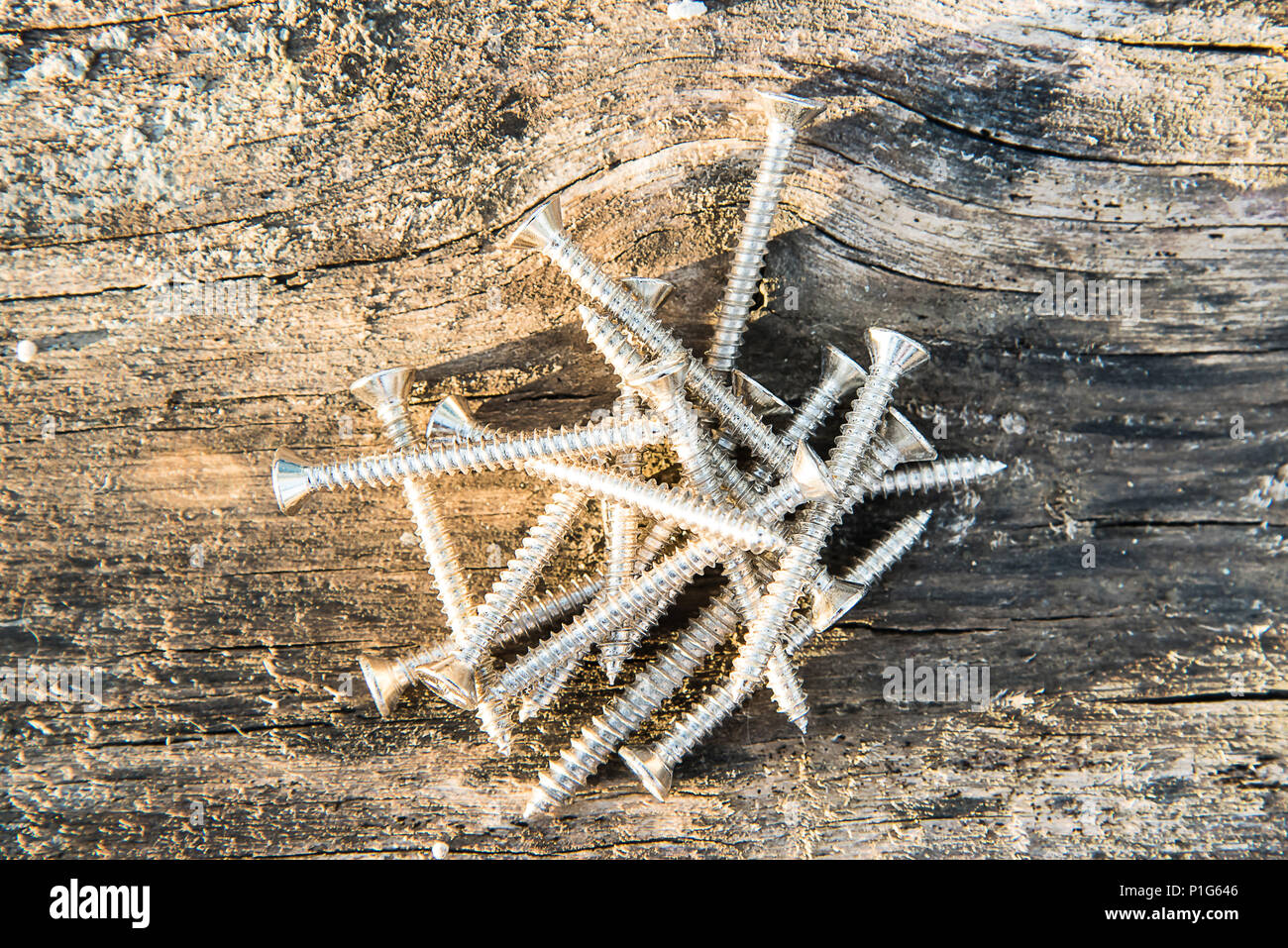 Tapping screws made of steel on wood background at gold sun light Stock ...