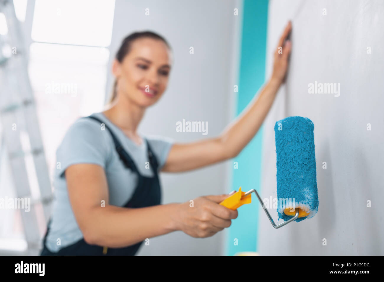 Inspired painter painting the walls in blue Stock Photo - Alamy