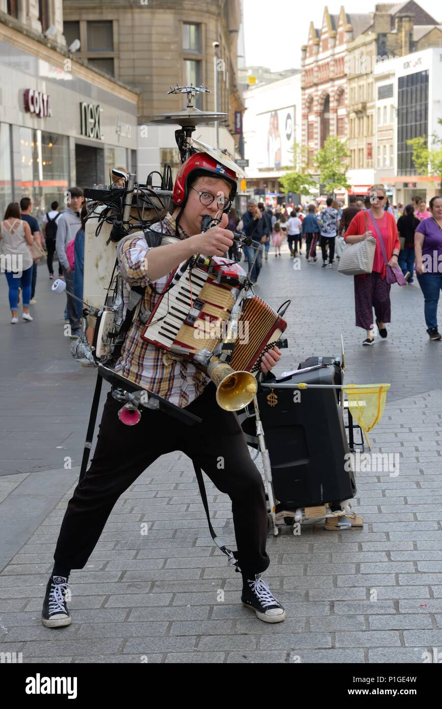 A young musician busking on a city centre street with his entertaining ...