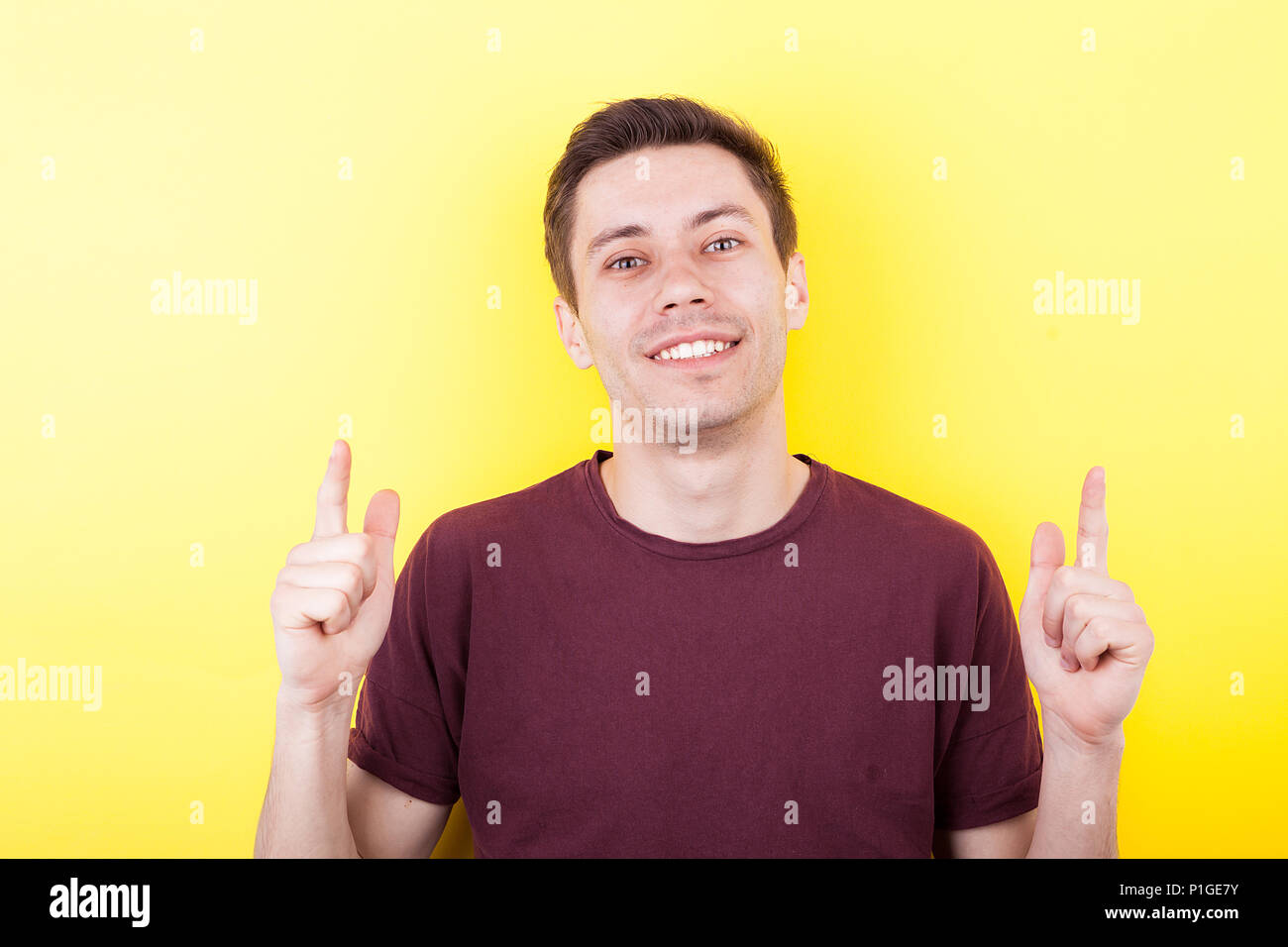 Happy guy pointing up on yellow background Stock Photo - Alamy