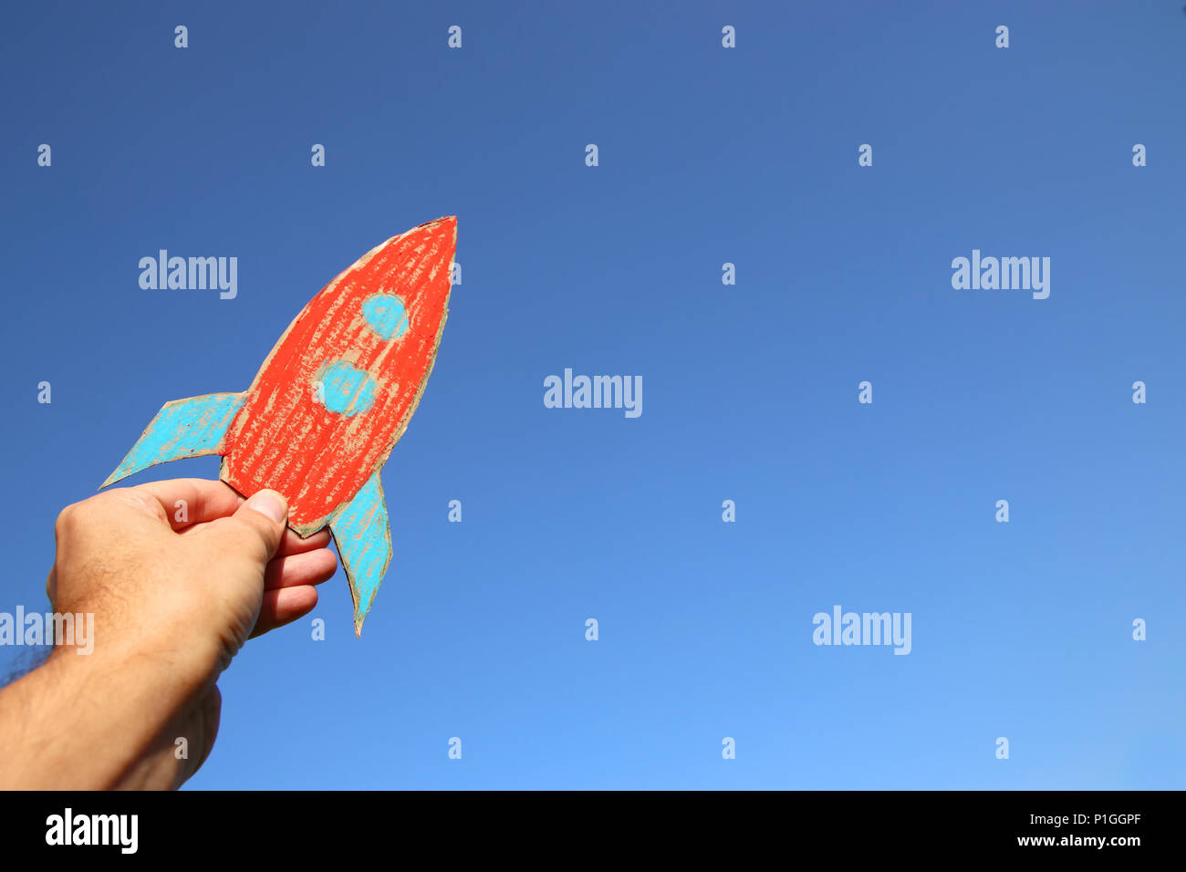 image of male hand holding a rocket against the sky. imagination and ...
