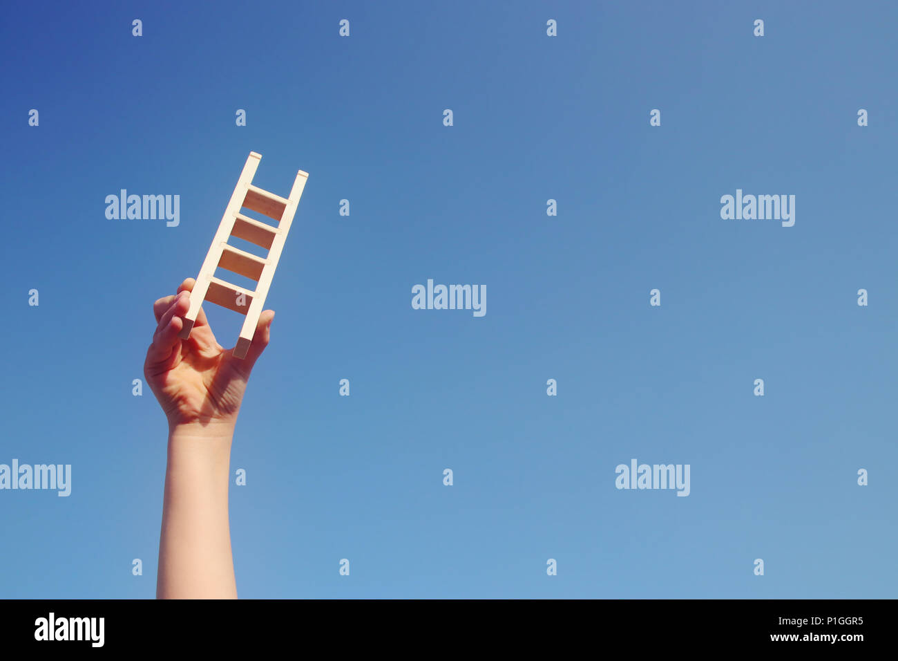 image of child hand holding a ladder against the sky. education and ...