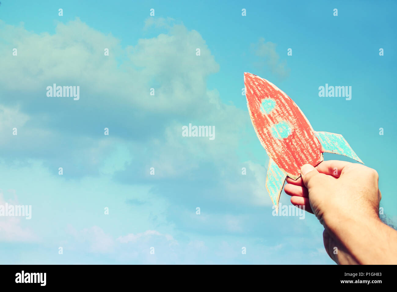 image of male hand holding a rocket against the sky. imagination and ...