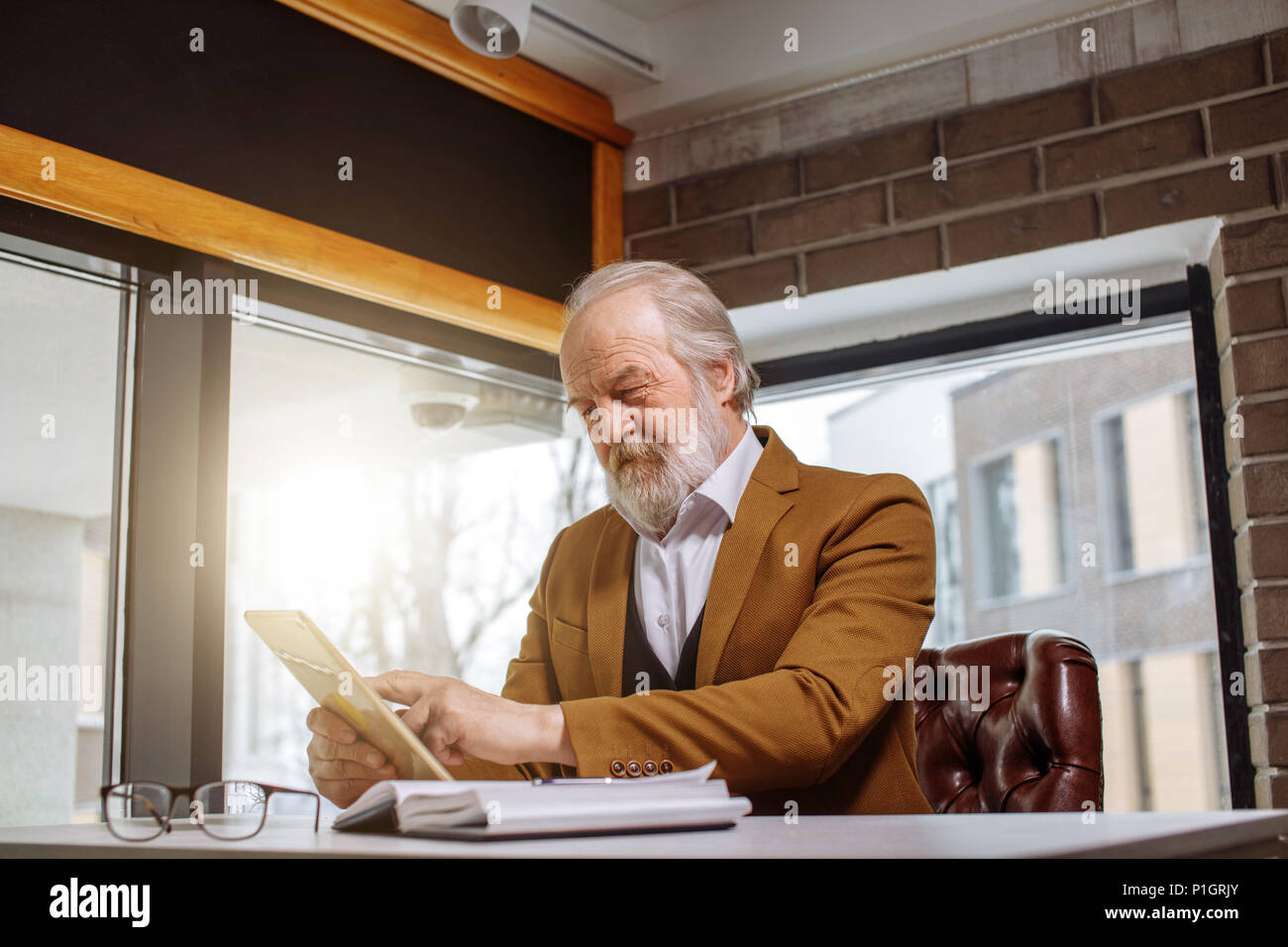 director in stylish orange suit looking at screen of the tablet Stock ...