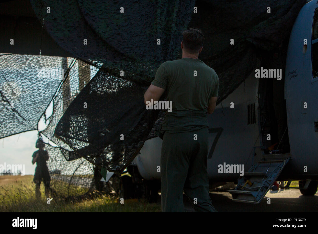 U.S. Marine Corps Capt. Gray Gish helps camouflage an MV-22B Osprey ...