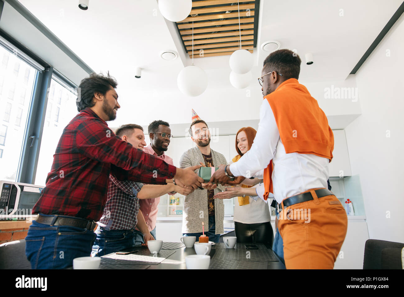 friendly team is presenting gift to handsome man who birthday at work ...