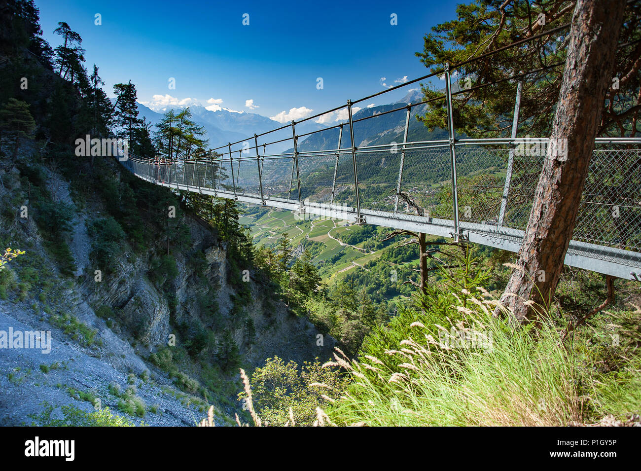Suspension bridge traversing a sheer rock face in the Swiss Alps ...