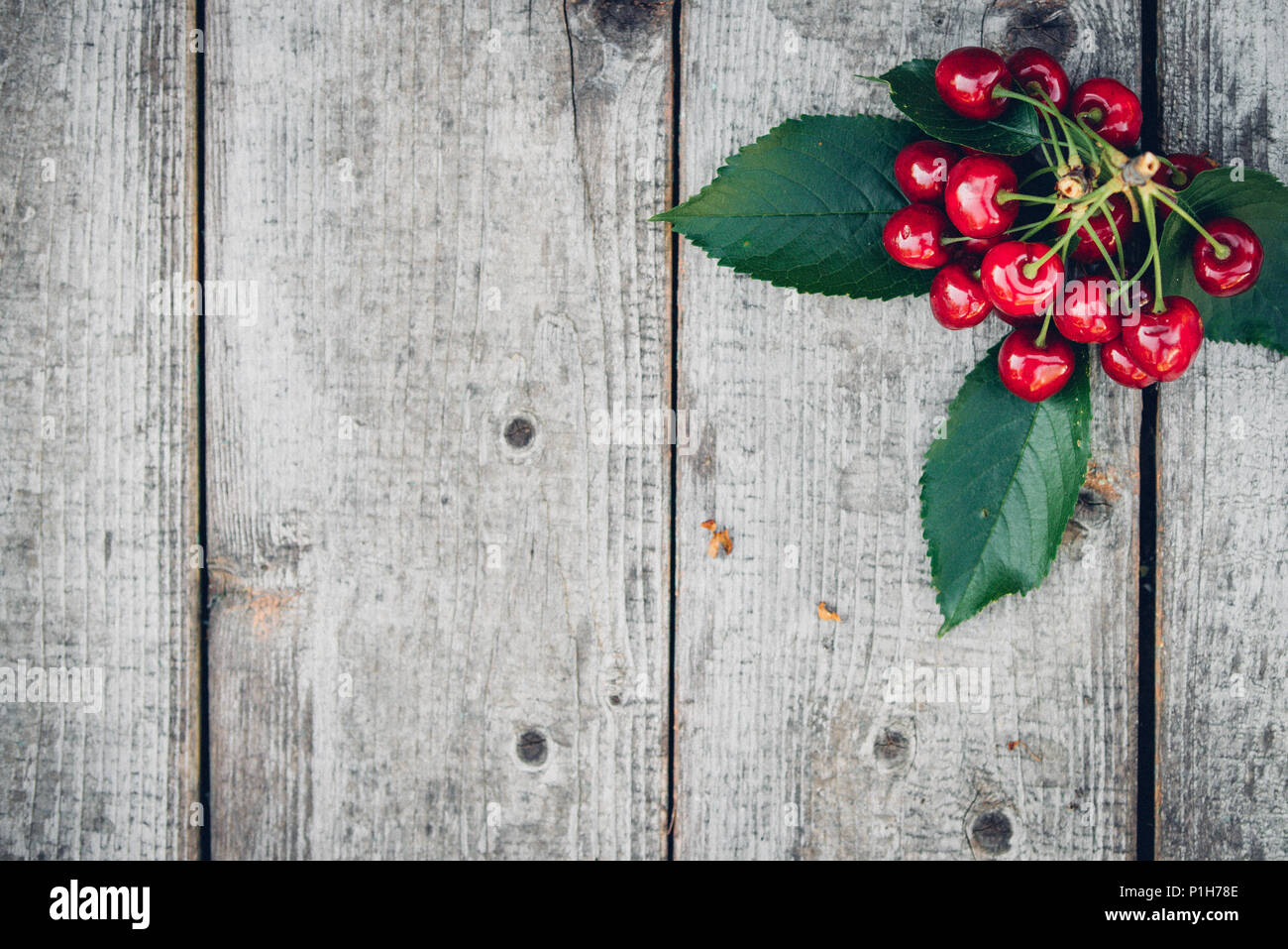 fresh red cherries on an old wooden table with green leaves, rustic ...