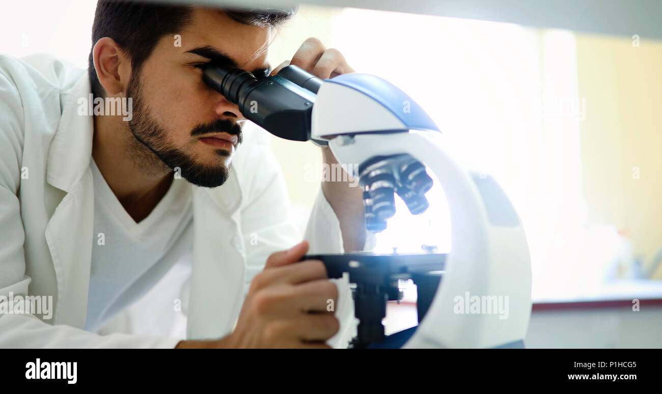 Young scientist looking through microscope in laboratory Stock Photo ...