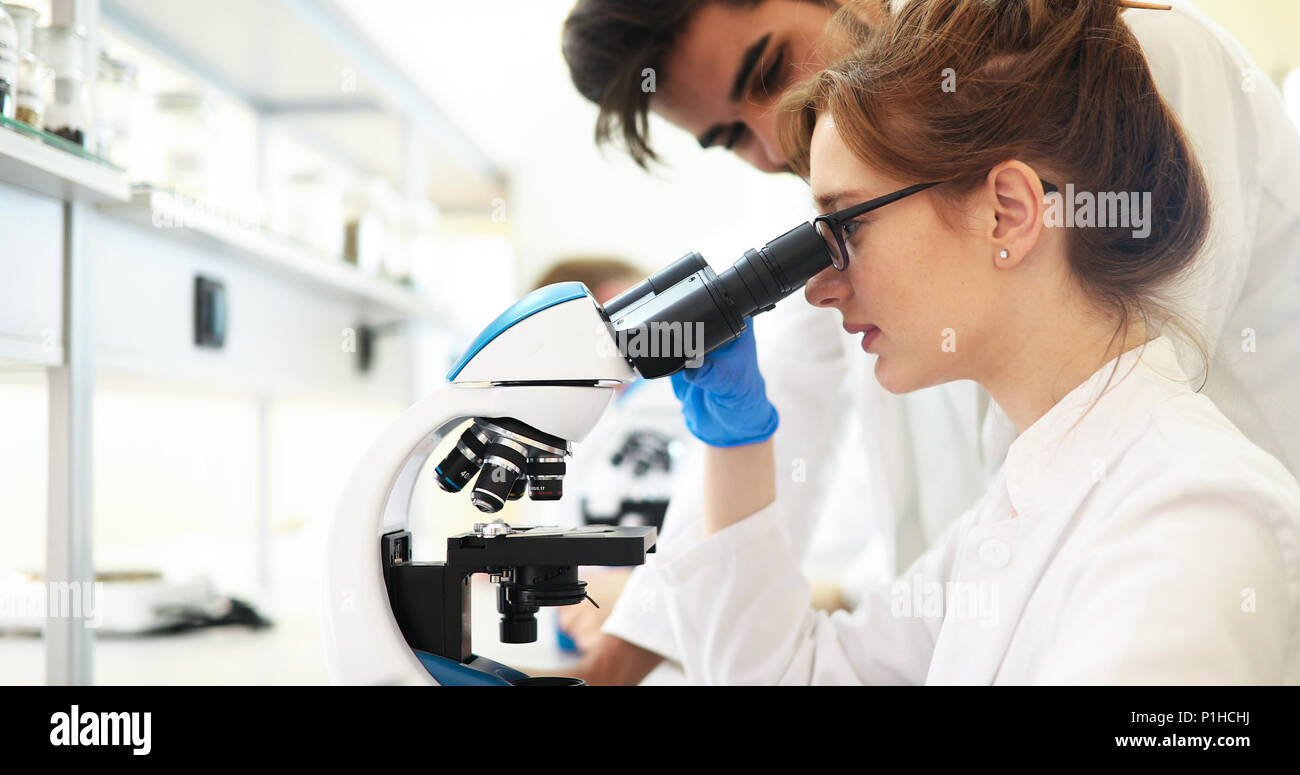 Young scientist looking through microscope in laboratory Stock Photo ...