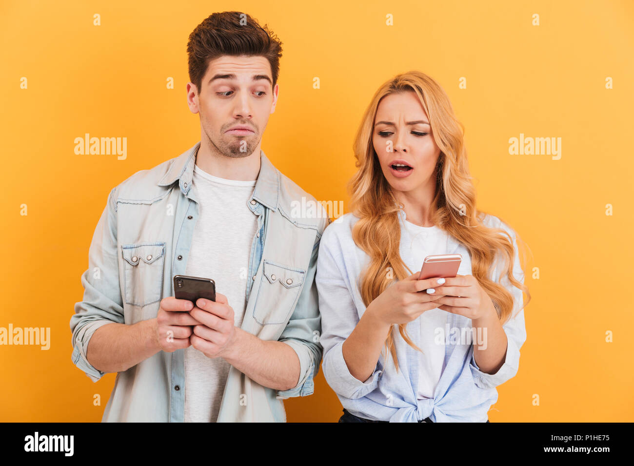Photo of curious man and woman frowning and peeking at each others cell ...