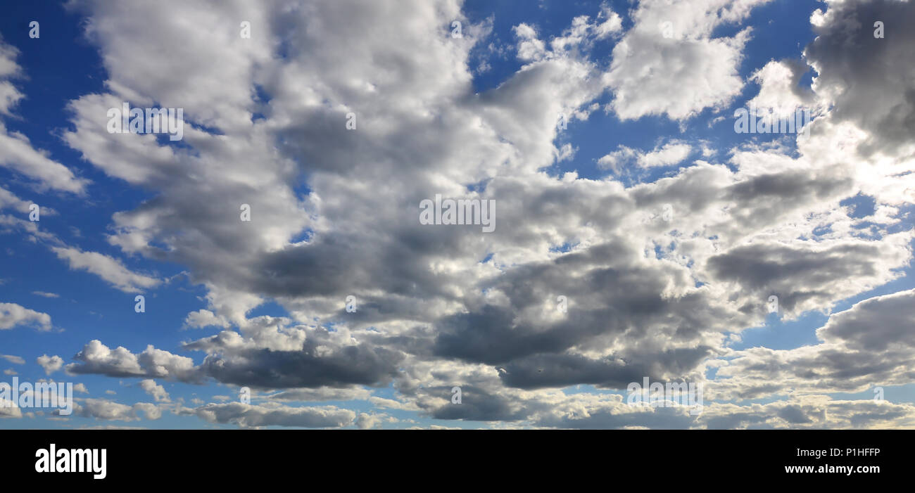A blue cloudy sky with many small clouds blocking the sun Stock Photo ...