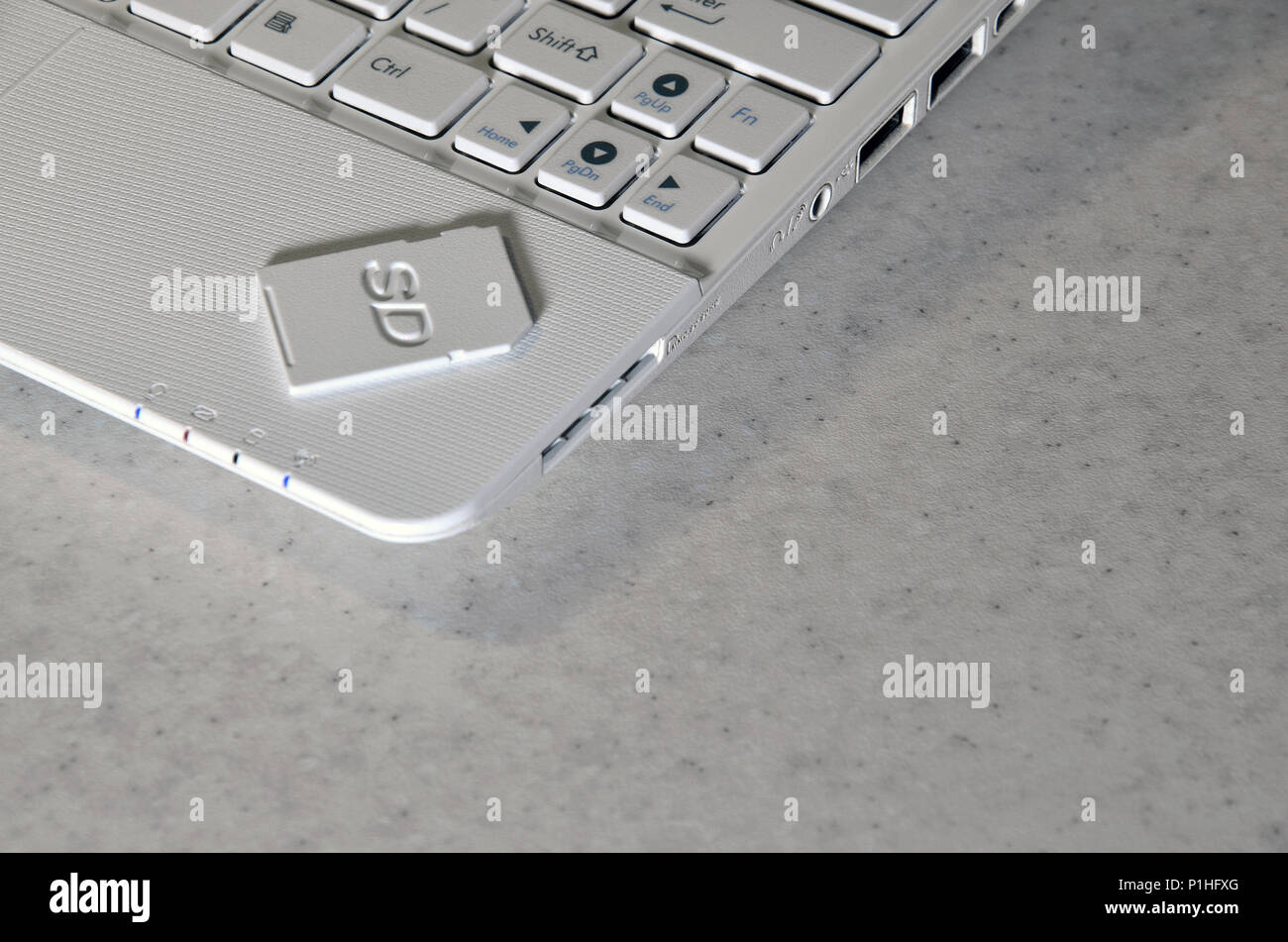 A compact SD memory card lies on a white netbook. The digital ...