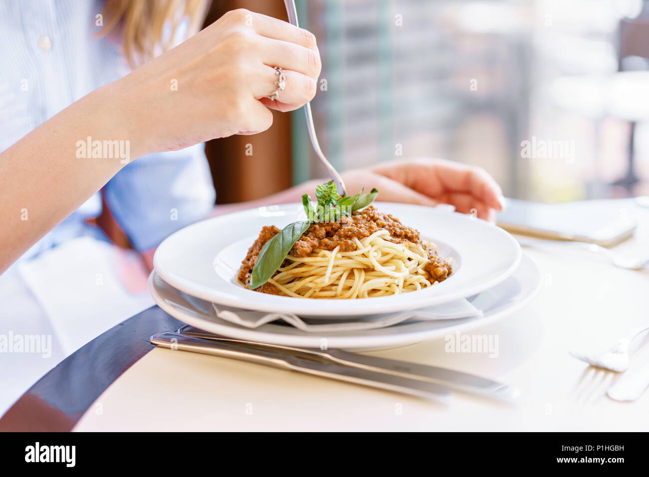 Young happy woman sitting at the table in cafe and enjoying the meal ...