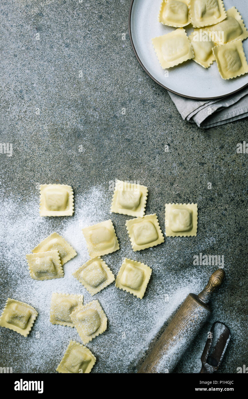 Fresh ravioli with flour on dark stone background, top view. Cooking ...
