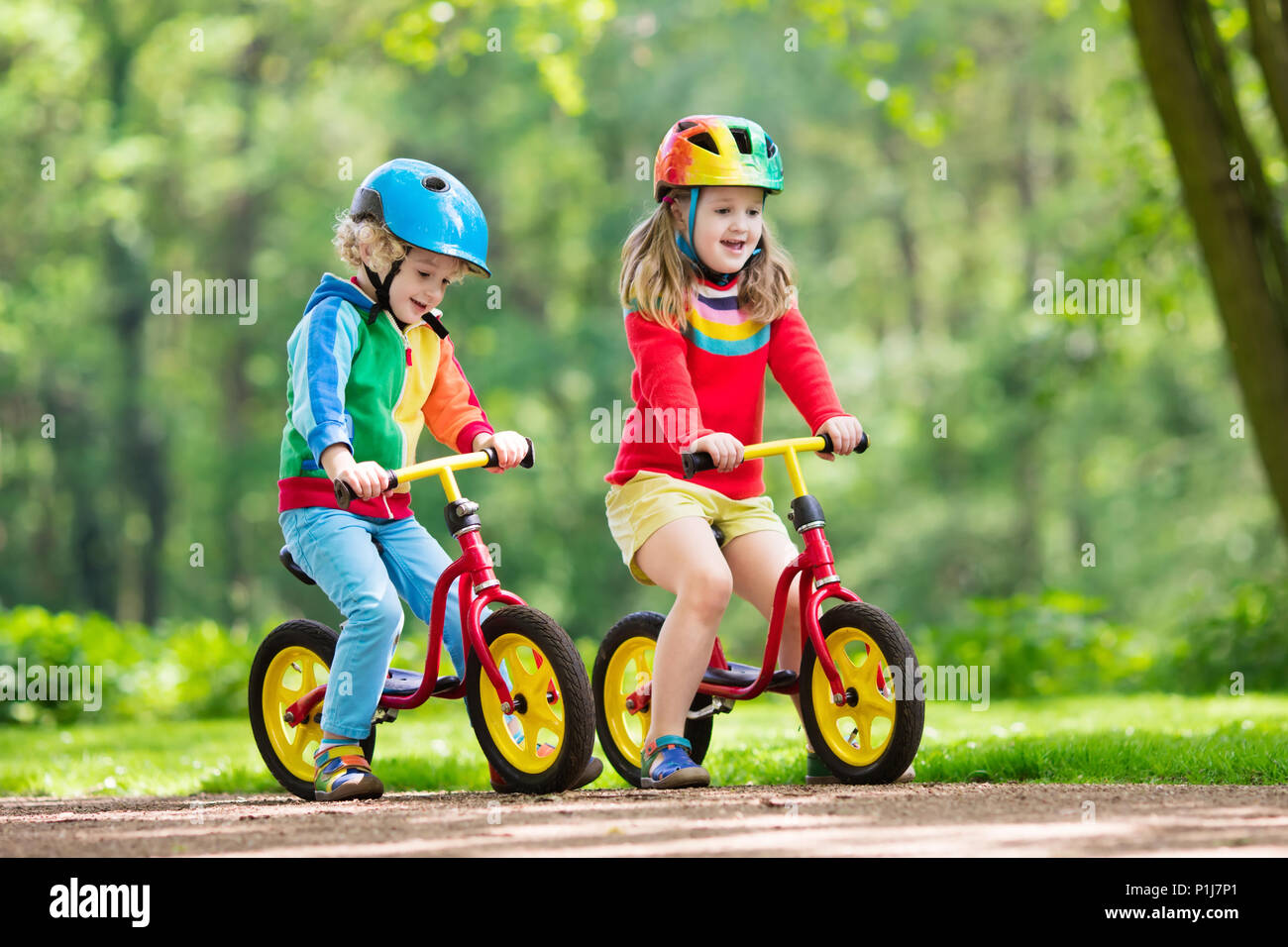 Children riding balance bike. Kids on bicycle in sunny park. Little ...