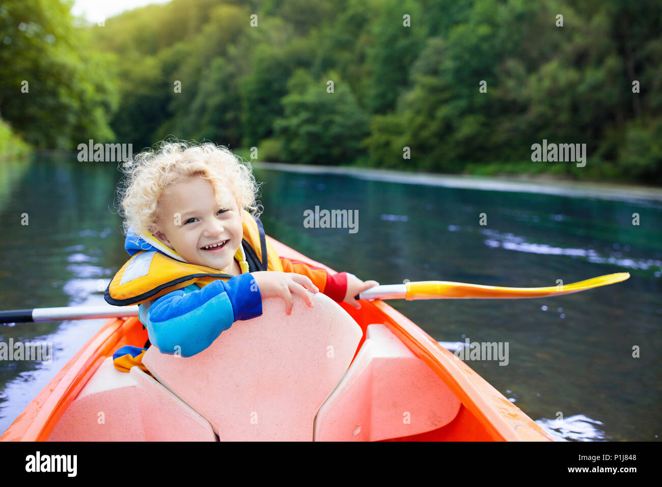 Child with paddle on kayak. Summer camp for kids. Kayaking and canoeing ...