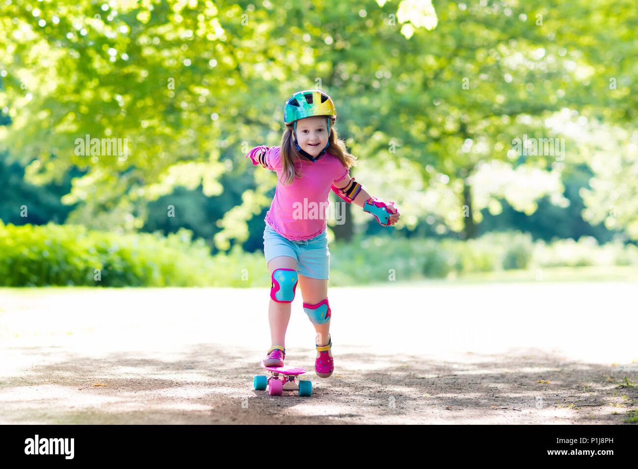 Child riding skateboard in summer park. Little girl learning to ride ...