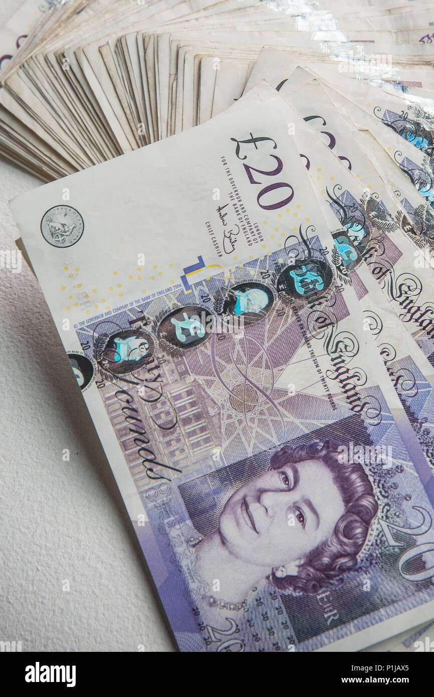A pile of British twenty pound notes on a white paper background Stock ...