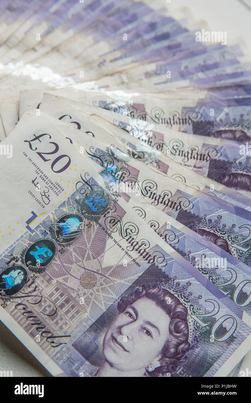 A pile of British twenty pound notes on a white paper background Stock ...