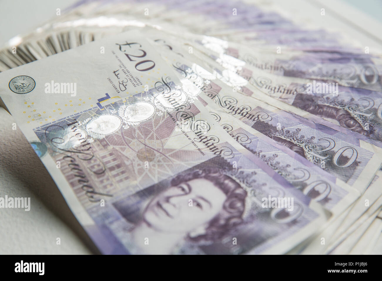 A pile of British twenty pound notes on a white paper background Stock ...