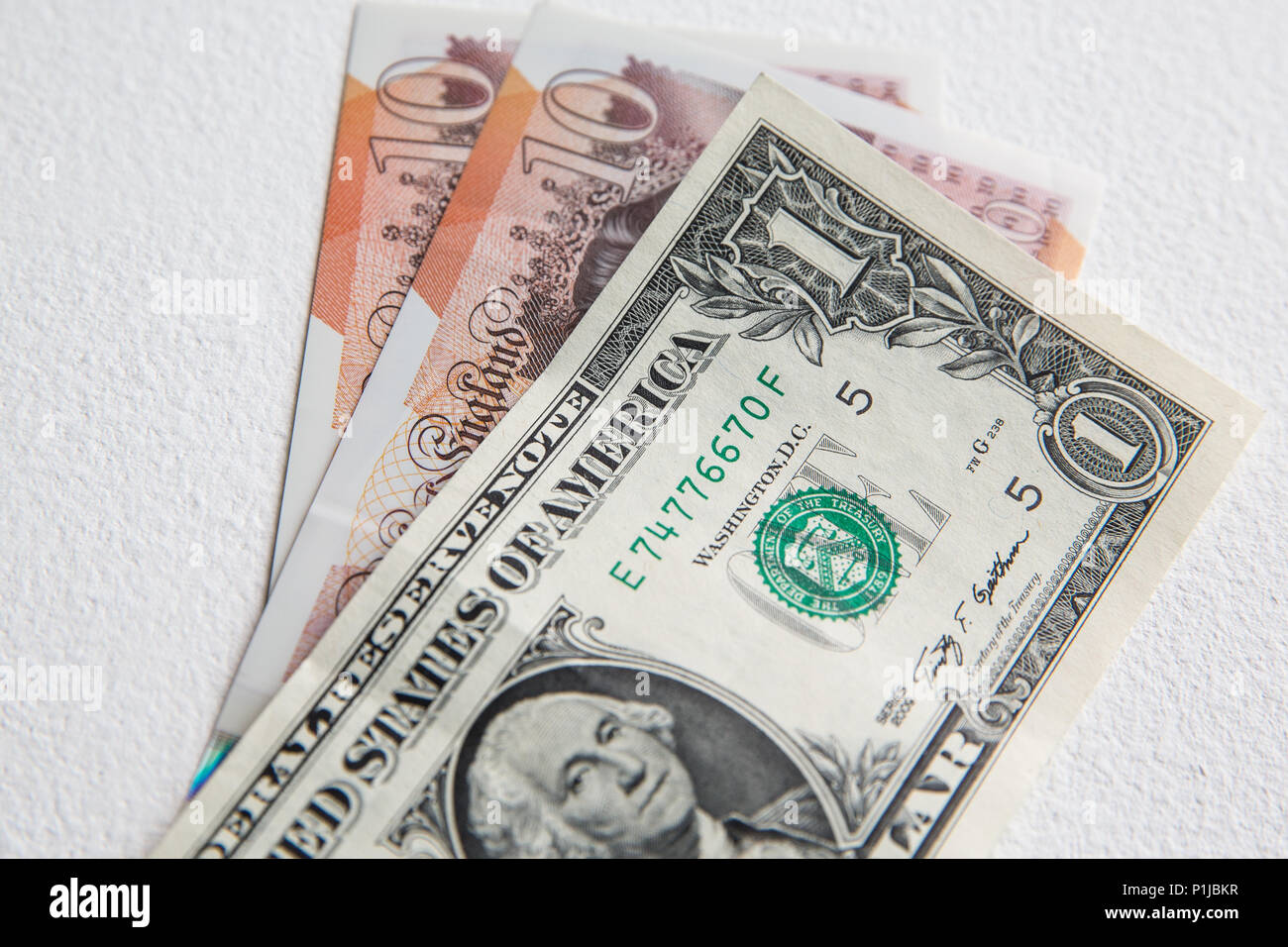 A pile of US one dollar notes and English ten pound notes in a pile on ...