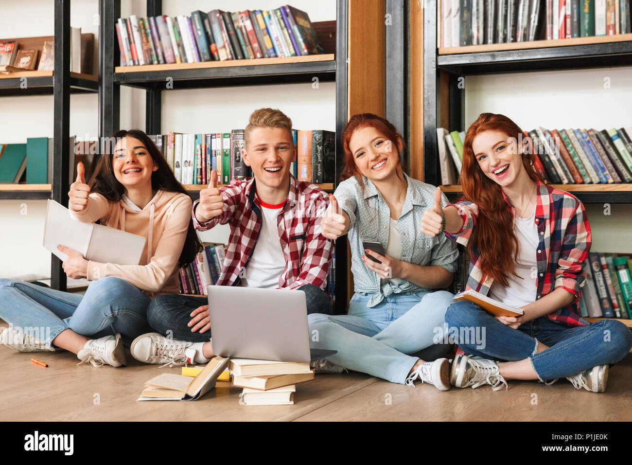 Group of confident teenagers doing homework while sitting on a floor at ...