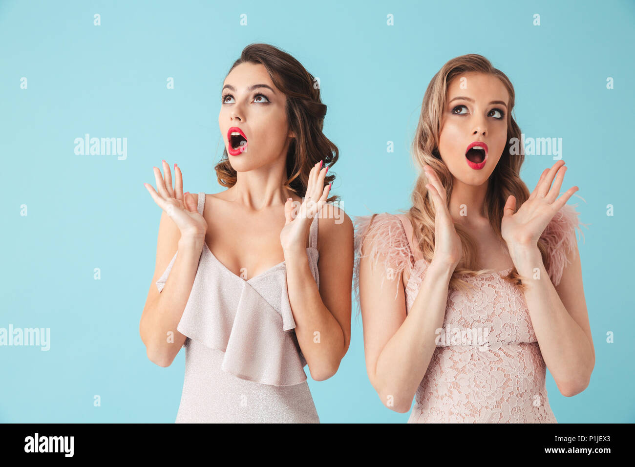Two worried confused women in dresses looking away with hands near head ...