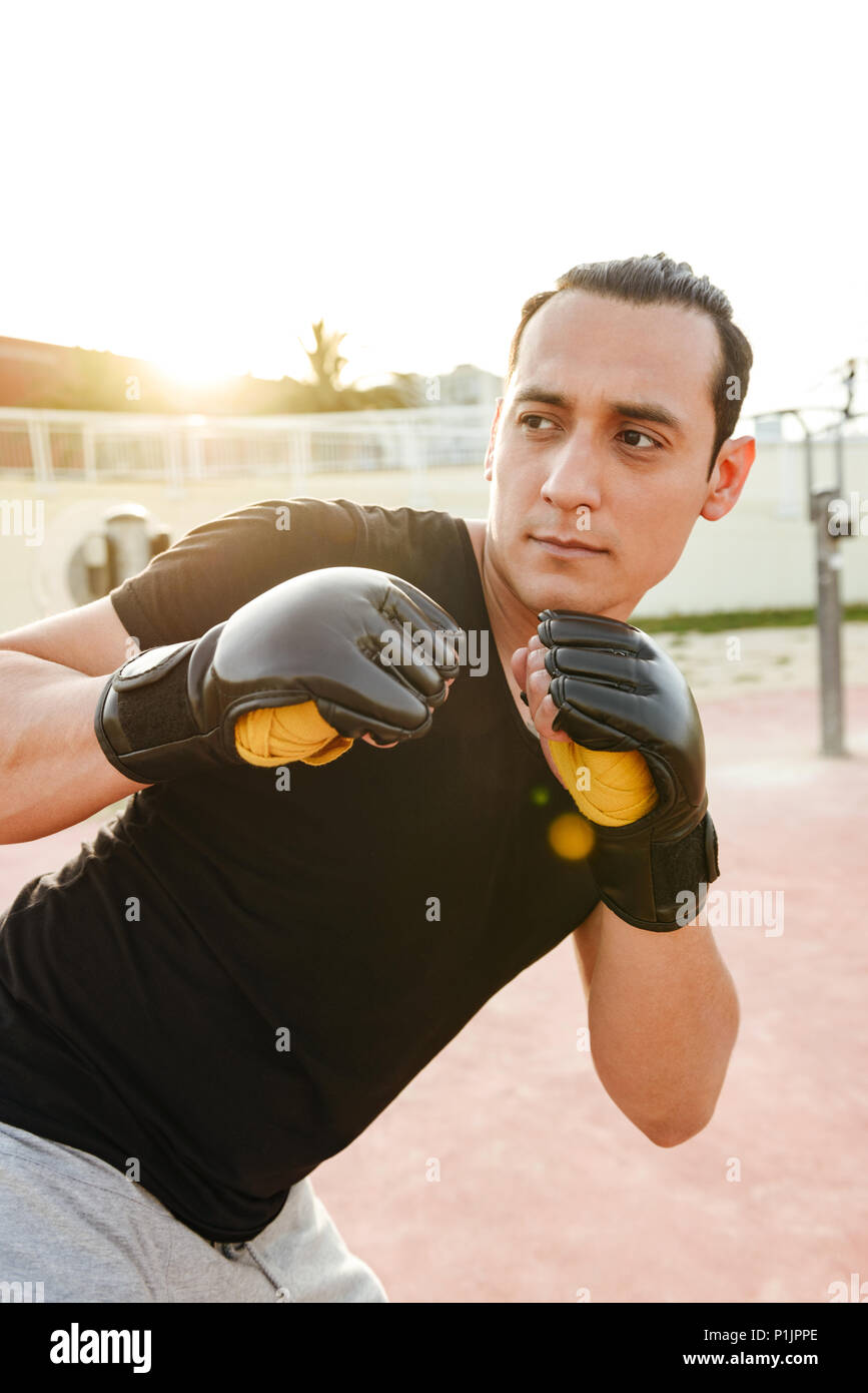 Photo of young concentrated strong sports man boxer outdoors make ...