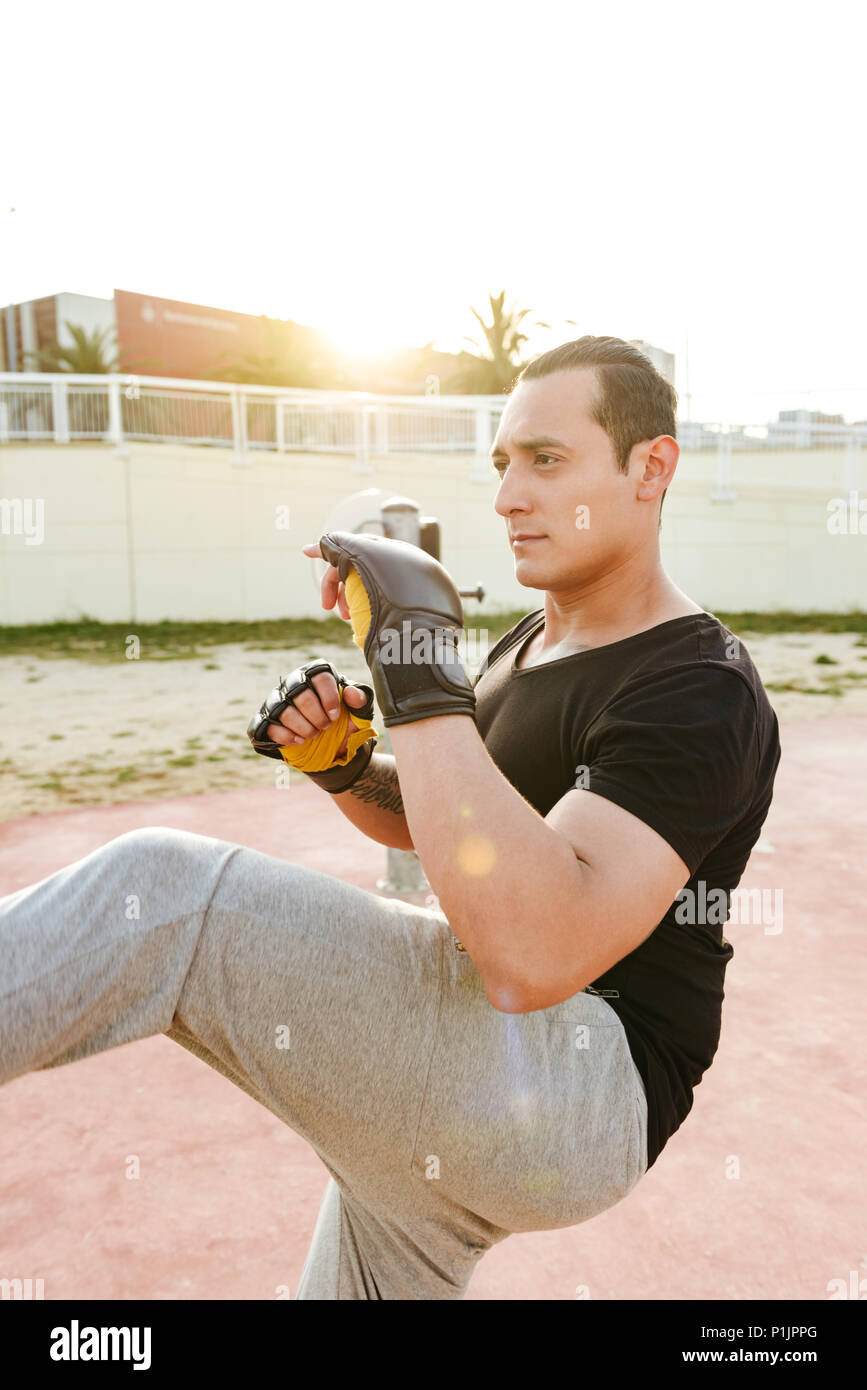 Image of young concentrated strong sports man boxer outdoors make ...