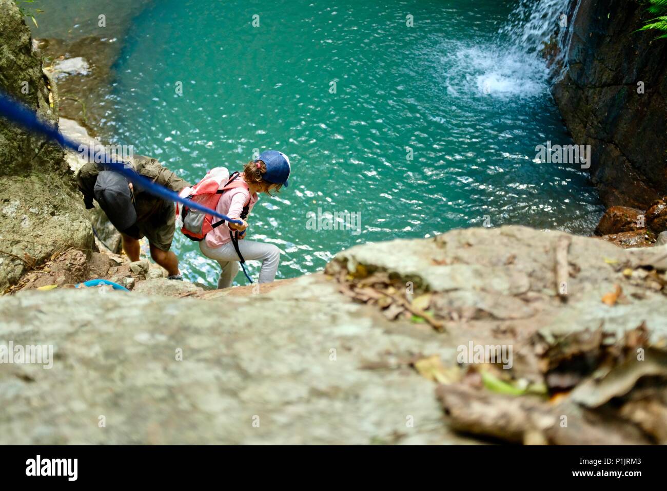 Father helps child to climb down rope at the tranquil blue waters of ...