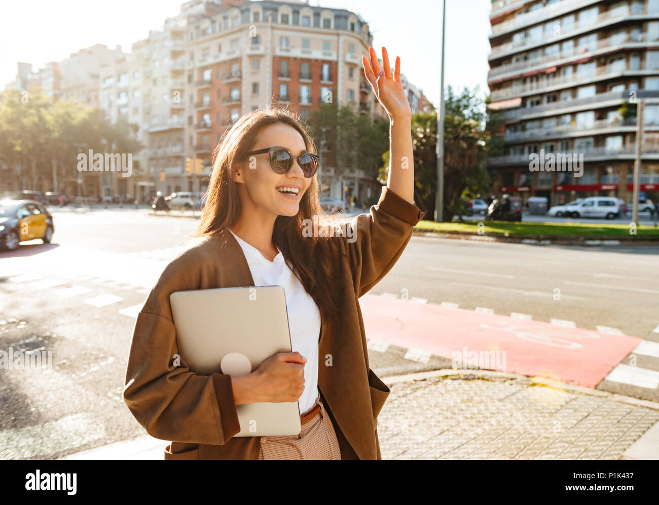 Image of amazing happy beautiful woman walking outdoors holding laptop ...