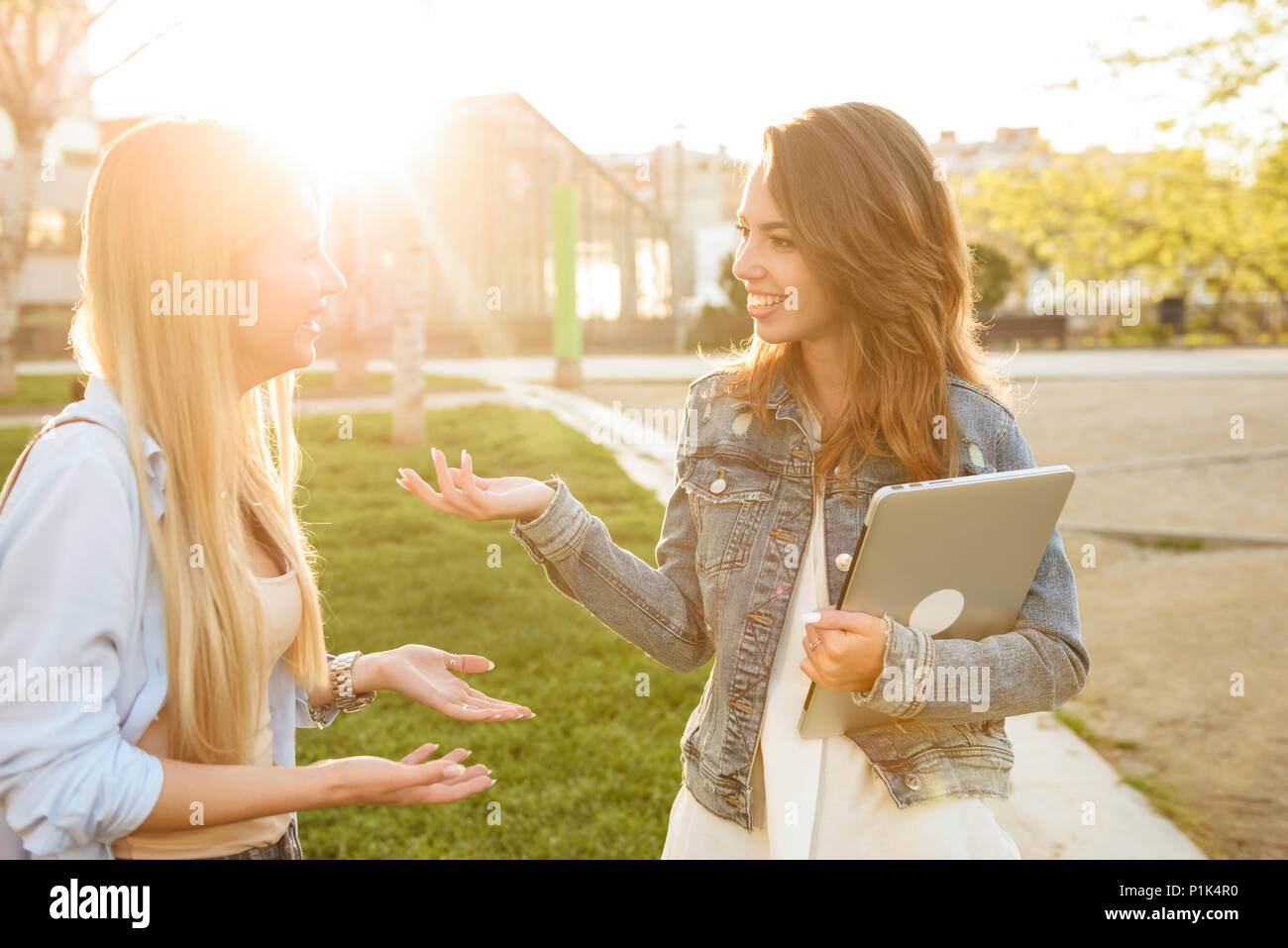 Image of happy two friends women in park outdoors holding laptop ...