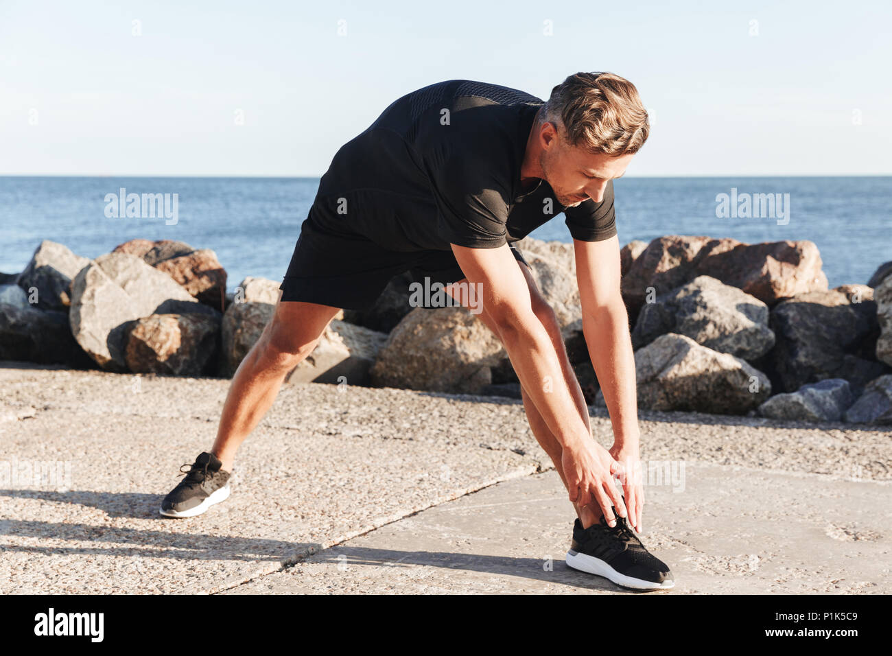 Handsome sportsman doing stretching exercises at the seaside Stock ...