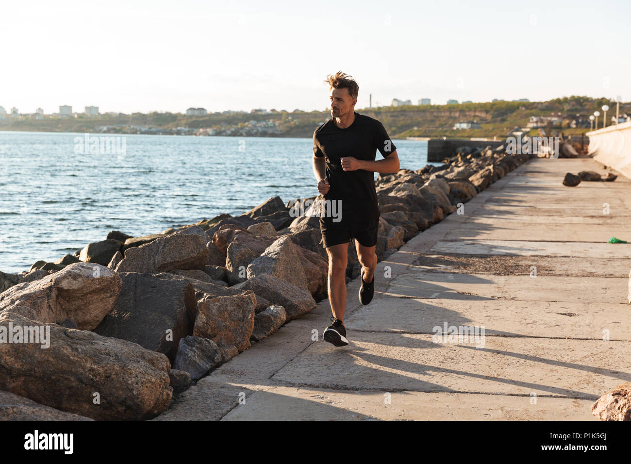 Fit young men jogging along beach hi-res stock photography and images ...
