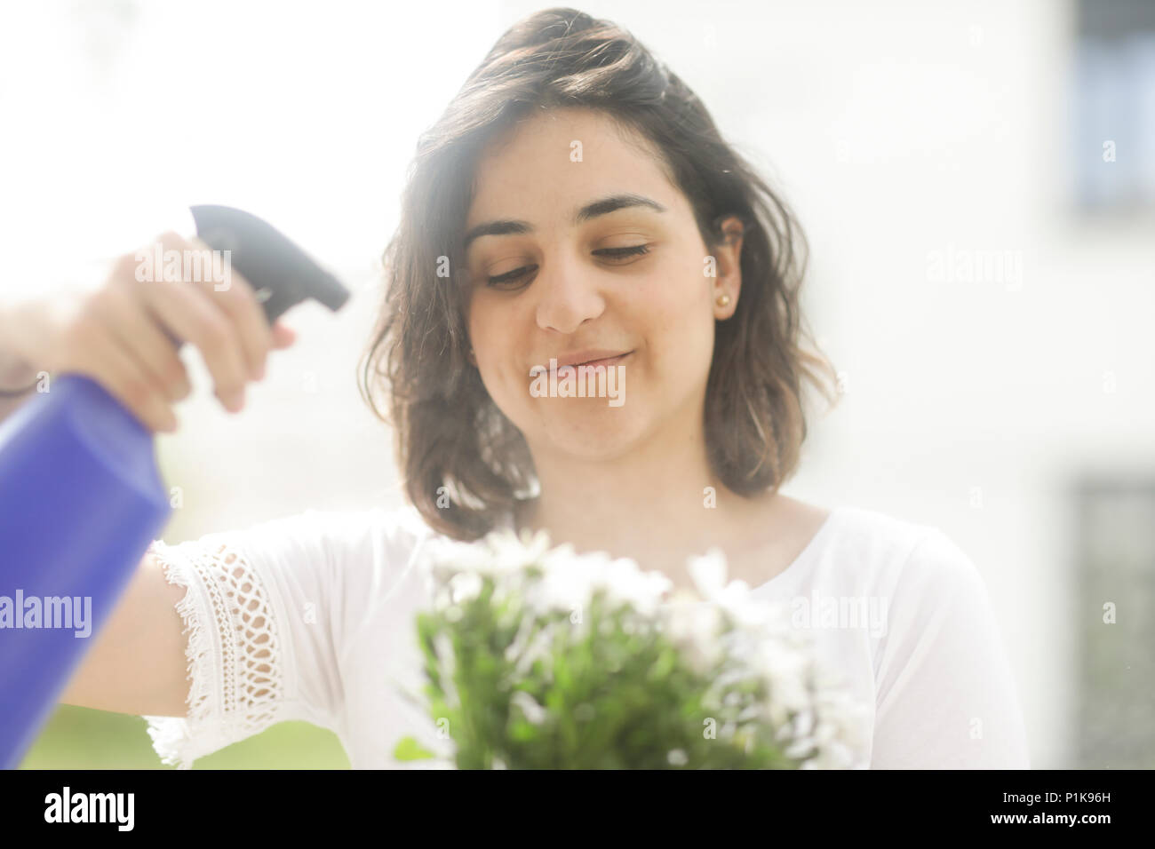 Woman spraying flowers with water in her garden Stock Photo - Alamy