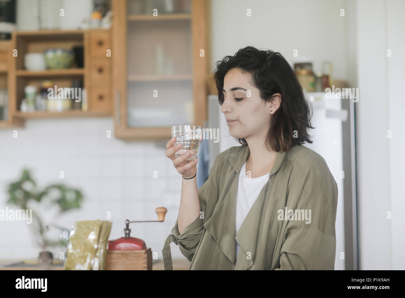 Woman standing in the kitchen drinking a glass of water Stock Photo - Alamy